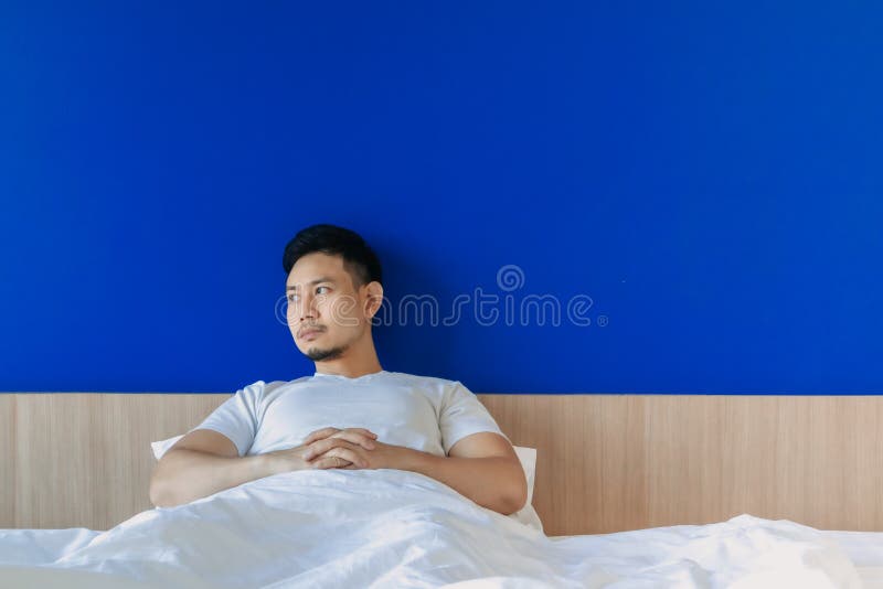 Serious and Grumpy Man Wake Up on the Bed on Blue Space Background ...