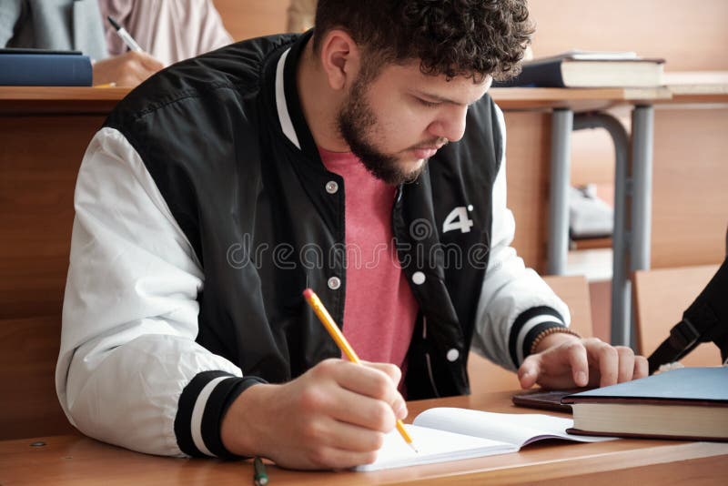Serious Guy in Casualwear Bending Over Desk and Making Notes in ...