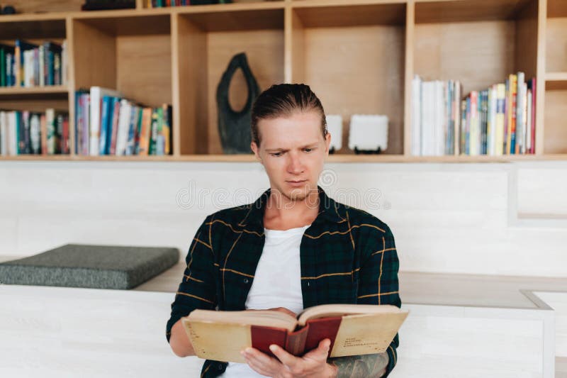 Serious Male Student Reading a Book in a Library Stock Photo - Image of ...