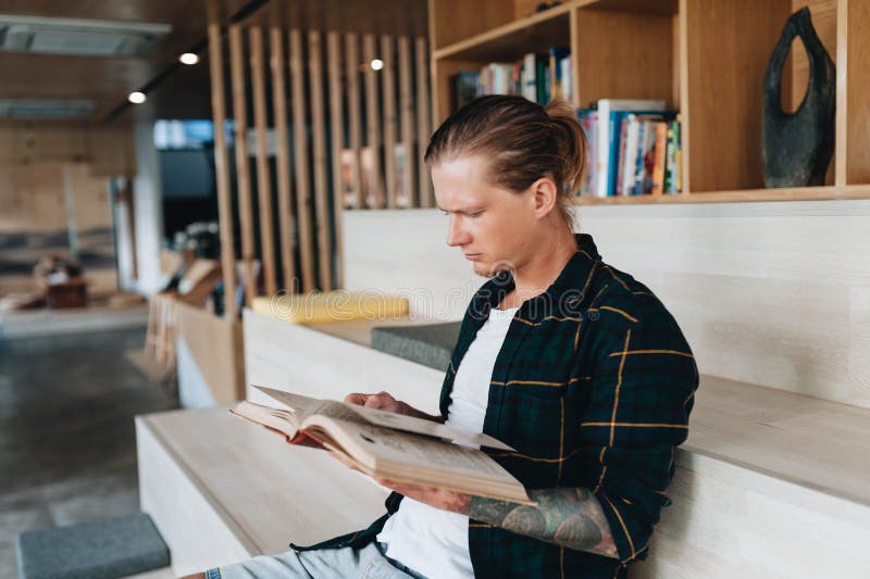 Serious Male Student Reading a Book in a Library Stock Image - Image of ...