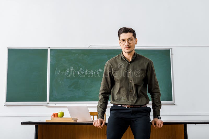 Serious Male Teacher in Formal Wear Looking at Camera and Standing Near ... Serious Male Teacher in Formal Wear Looking at Camera and Standing Near ...