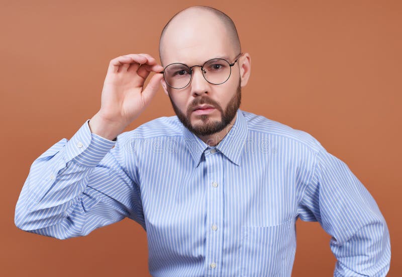 A Serious Man With A Beard And Round Glasses Bent Down In The Camera