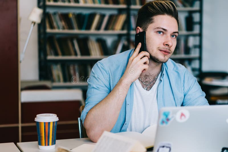 Serious Man Speaking on Smartphone at Table while Studying in Library ...