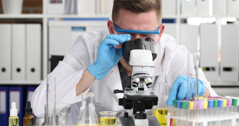 Serious Man Studies Liquid Specimen in Test Tube with Microscope Stock ...