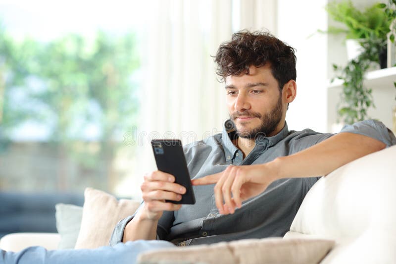 Serious Man Using Phone on a Couch at Home Stock Image - Image of ...