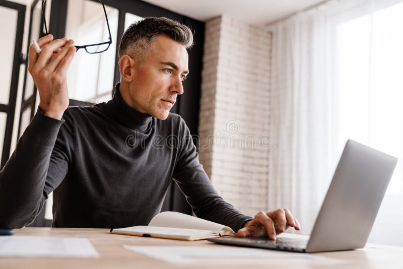 Serious Man Working with Laptop and Planner while Sitting at Table ...