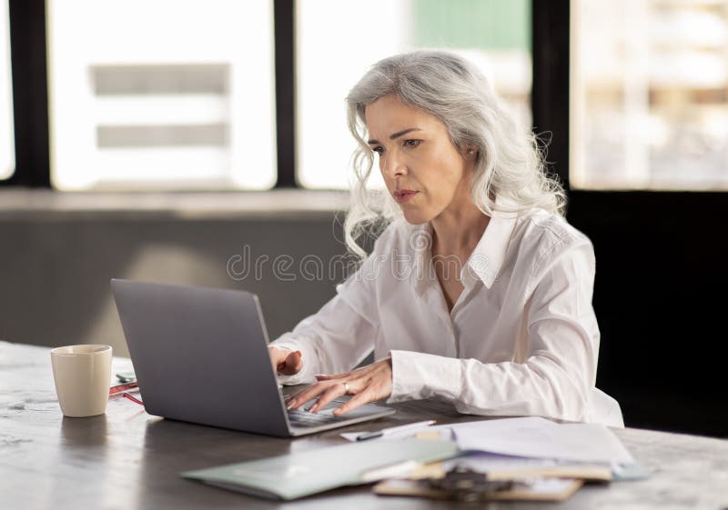 Serious Mature Businesswoman Using Laptop Engaging in Office Work ...