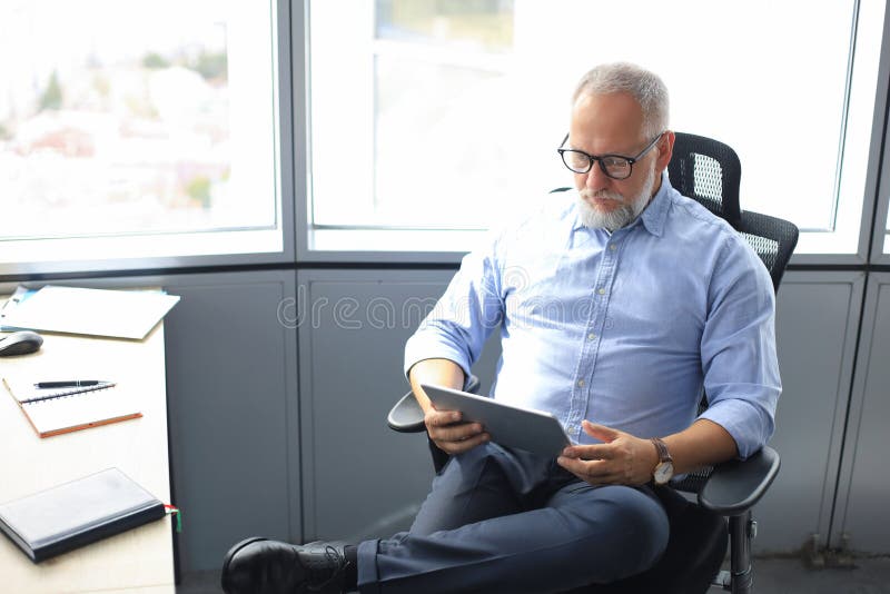Serious Mature Financial Advisor Sitting at the Table and Checking ...