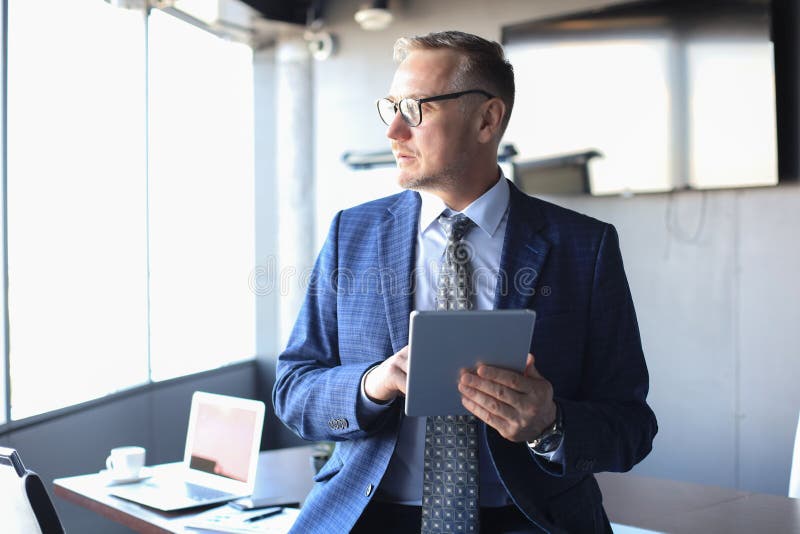 Serious Mature Financial Advisor Sitting at the Table and Checking ...