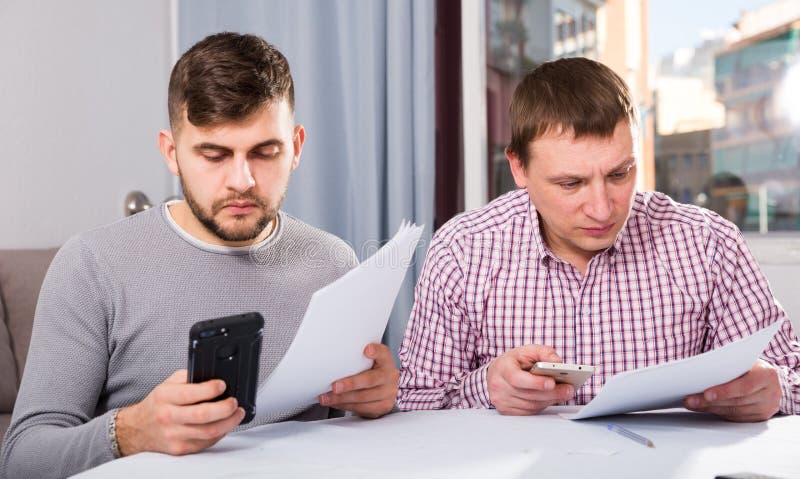 Serious Men with Documents and Phone at Home Table Stock Image - Image ...