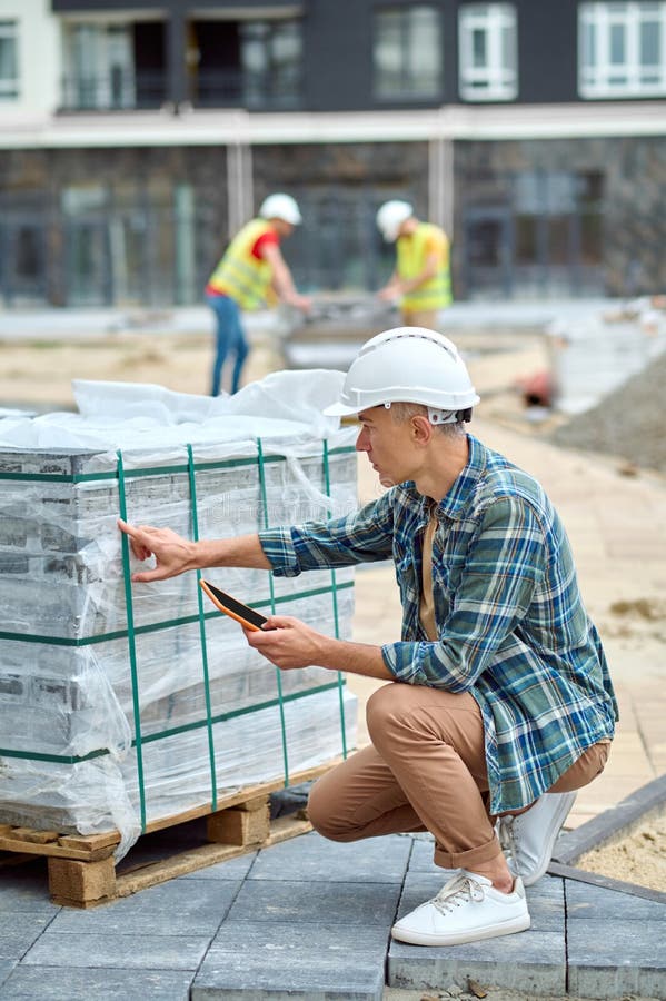 Engineer in a Protective Helmet Inspecting the Building Materials ...
