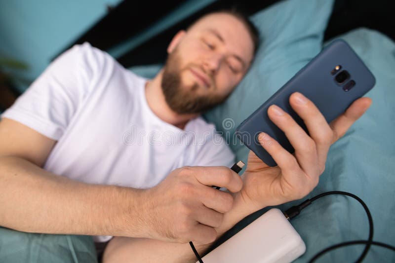 Serious Millennial Man Using Mobile Phone in Bed Connect it To a ...