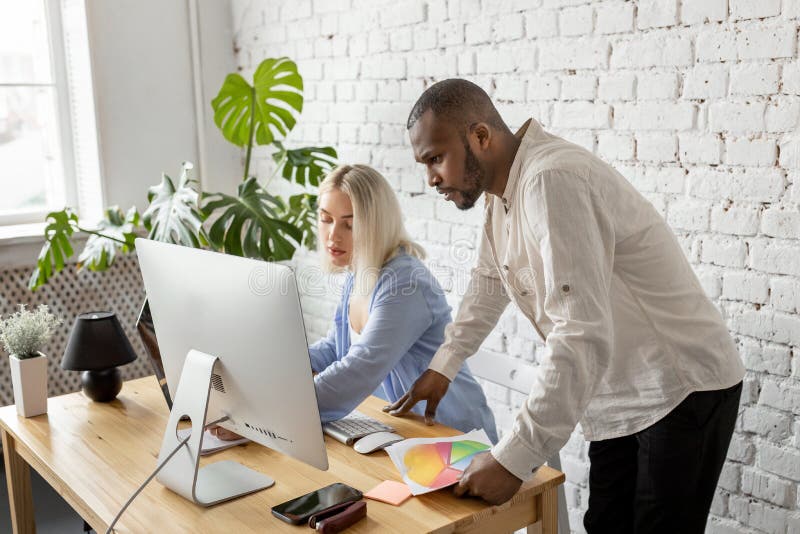 Serious Mixed Race Colleagues Using Computer, Working on Report ...