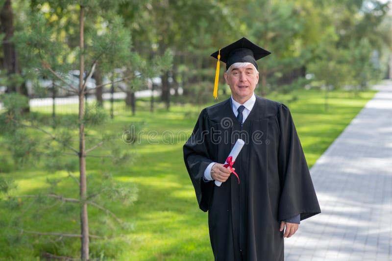 Serious Old Man in Graduation Gown Holding Diploma Outdoors. Stock ...