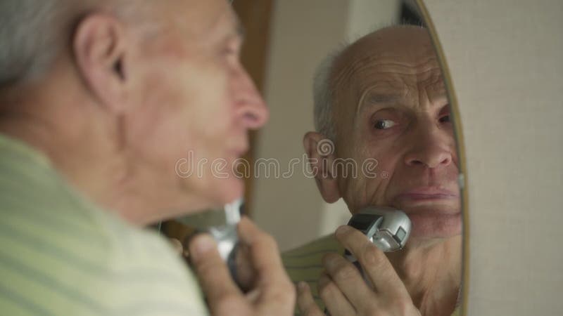 Serious Older Man Looking in His Reflection in Mirror and Shaving ...