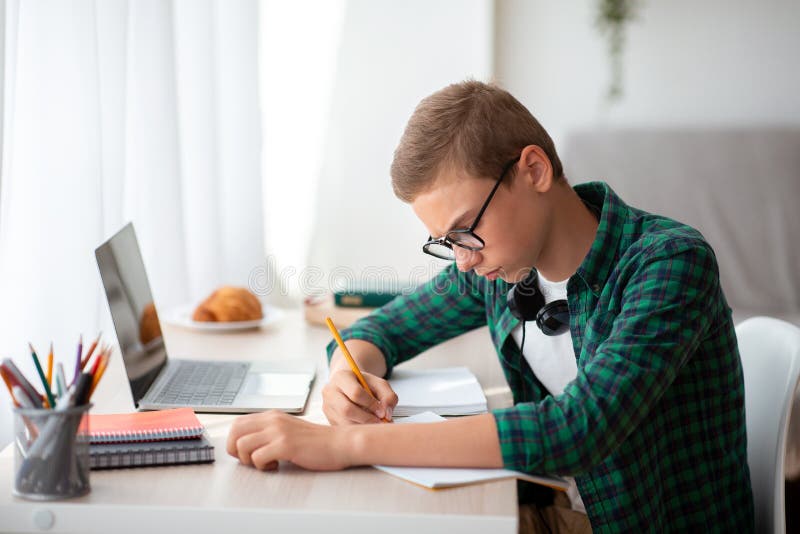 Serious Schooler Doing Homework at His Room, Writing in Notebook Stock ...