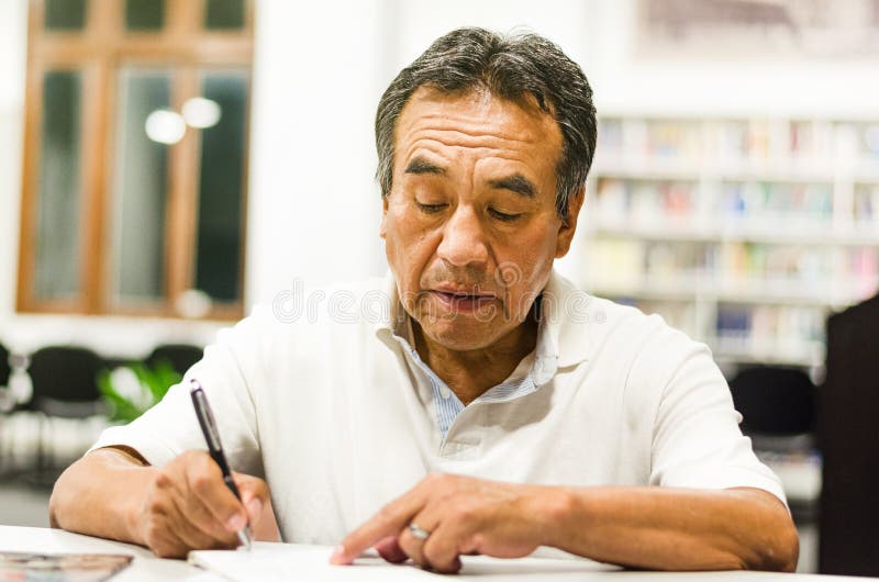 Serious Senior Man Sitting on a Library Bench Writing in His Book ...