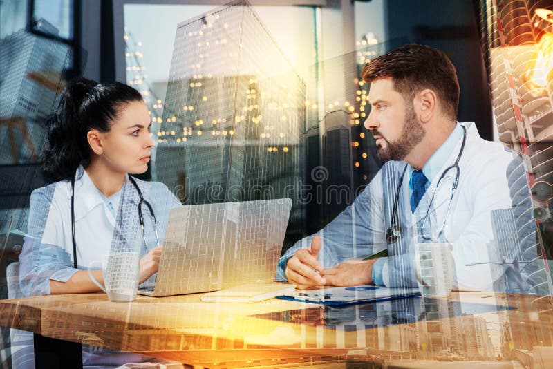 Serious Smart Doctors Looking at Each Other while Having an Important ...