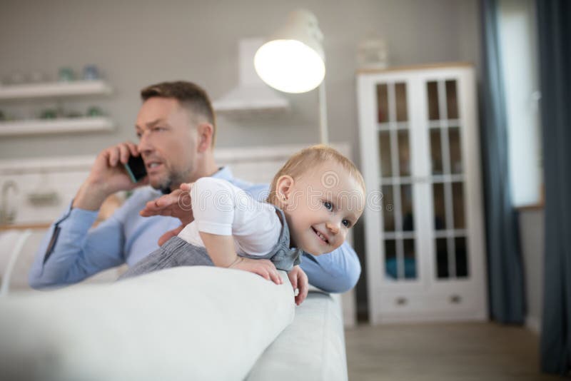 Man in a Blue Shirt Speaking on the Phone and Looking Serious Stock ...