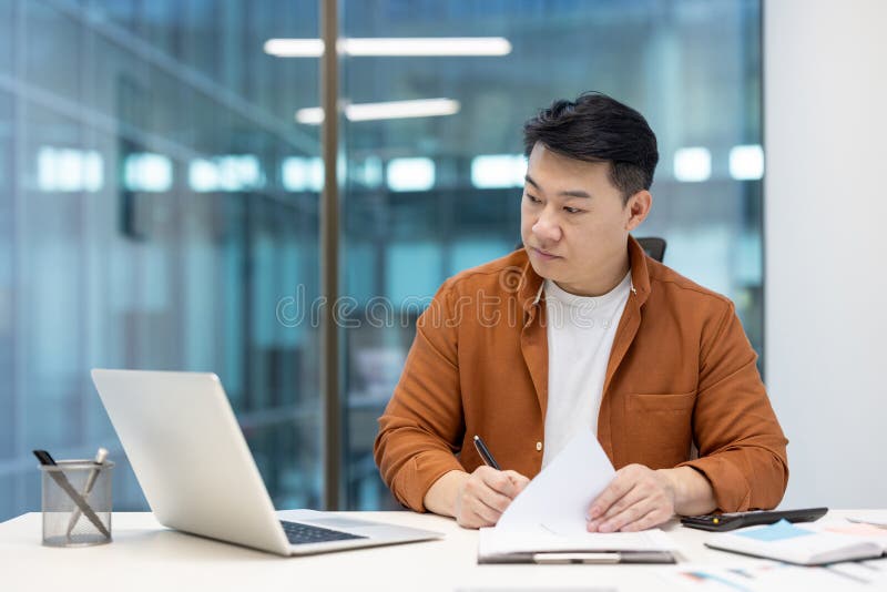 Serious Thinking Man Doing Paperwork Inside Office. Asian Man Working ...