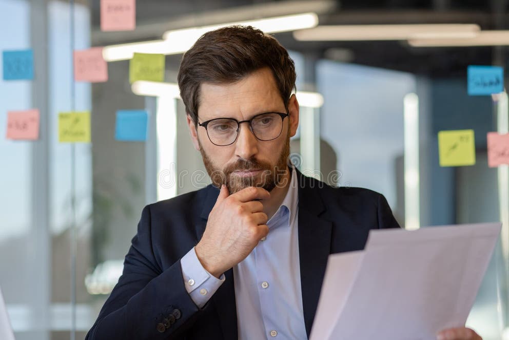 Serious Thinking Mature Businessman Analyzing Documents in Modern ...