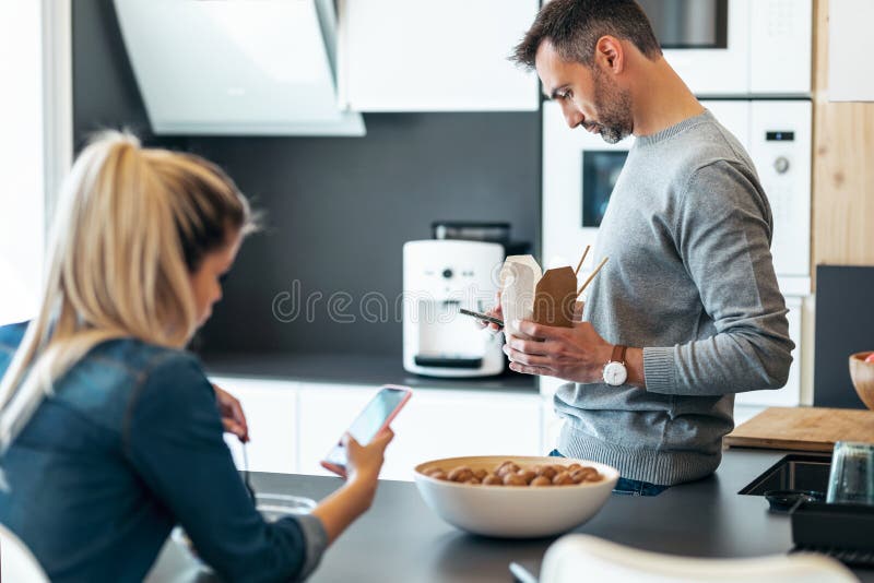 Serious and Unhappy Young Couple Eating while Using Smartphone in the ...