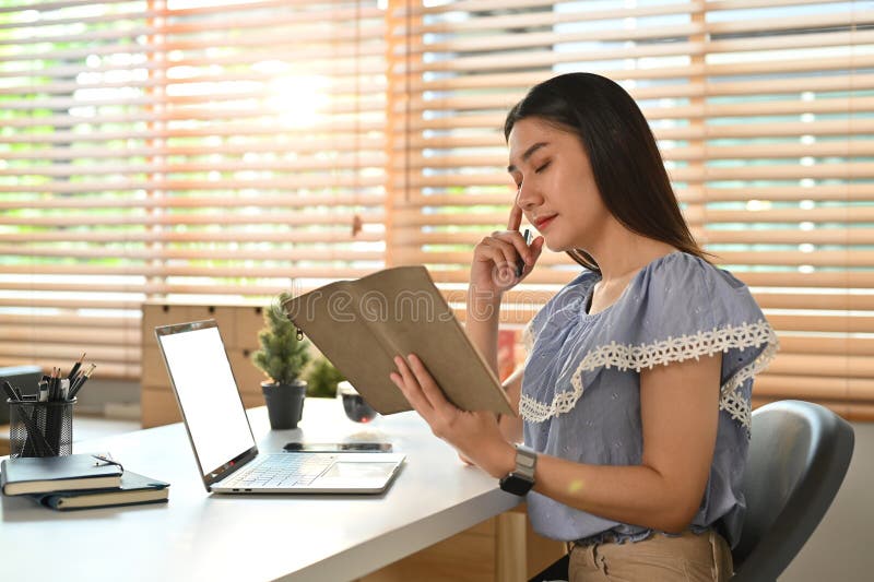 Serious Young Asian Female Entrepreneur Reading Notes in Planner or ...