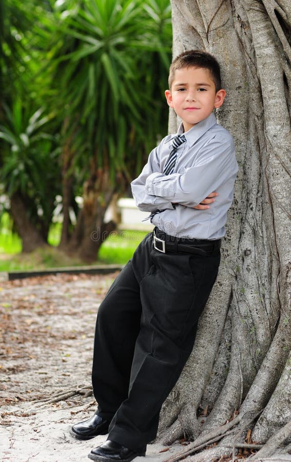 Serious Young Boy Leaning Against Tree Stock Photo - Image of outdoors ...