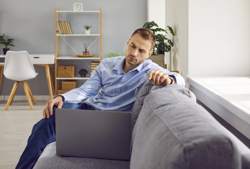 Serious Young Businessman Sitting on Couch, Using Notebook Computer ...