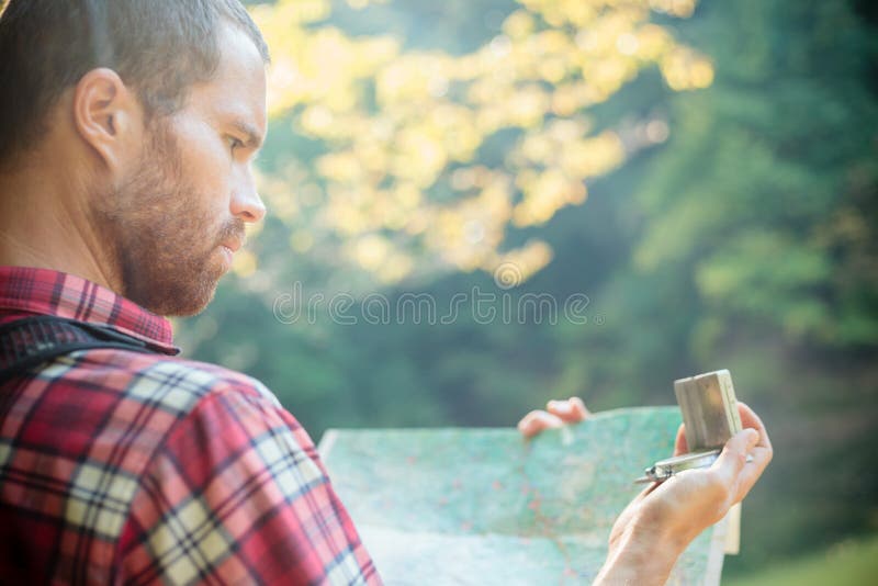 Serious Young Man Navigating Using Compass and a Map. Hiking through ...
