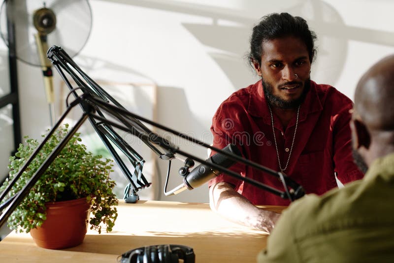 Serious Young Man Sitting in Front of Microphone and Looking at Guest ...