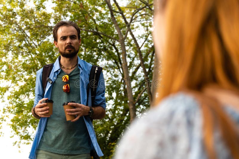 Serious Young Man with Two Coffee Cup Standing Against Young Girlfriend ...