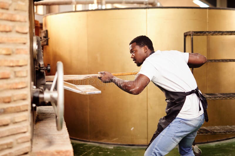 We only Serve Freshness. a Male Baker Placing Bread in a Oven. Stock ...
