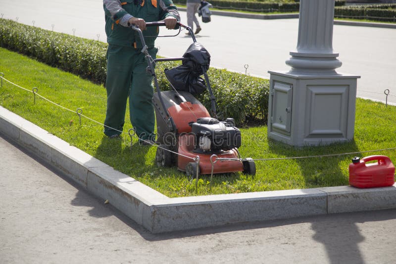 A Service Worker Mows the Lawn with a Lawn Mower Stock Photo - Image of ...