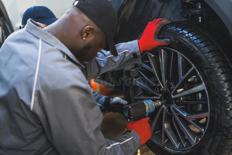 Serviceman Balancing a Wheel with a Tool, Medium Side View, Auto Repair ...
