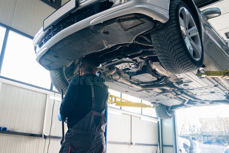 Serviceman Checks Car Suspension on a Column Lift in Car Service Stock ...