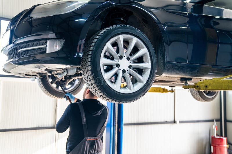 Serviceman Checks Car Suspension on a Column Lift in Car Service Stock ...