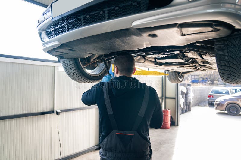 Serviceman Checks Car Suspension on a Column Lift in Car Service Stock ...