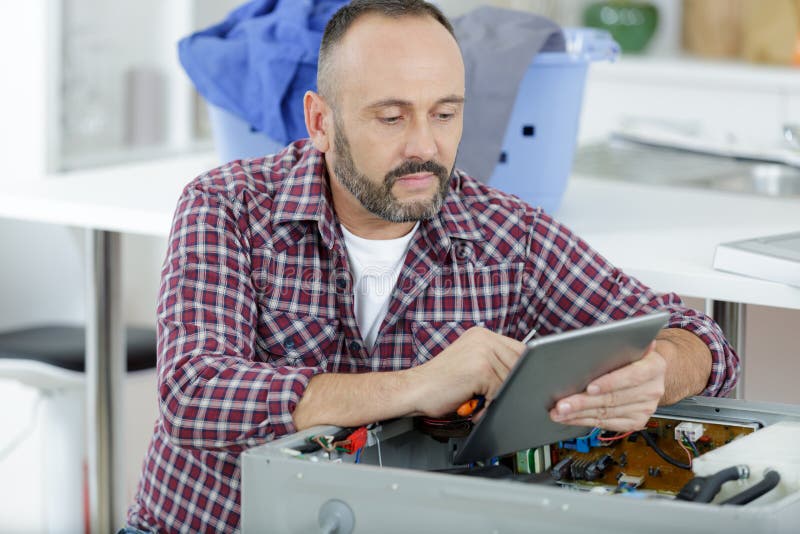 Serviceman Using Tablet To Diagnose and Repair Appliance Stock Image ...