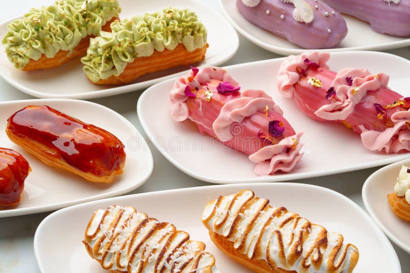 Set of Colored Eclairs with Whipped Cream on White Plates Stock Photo ...
