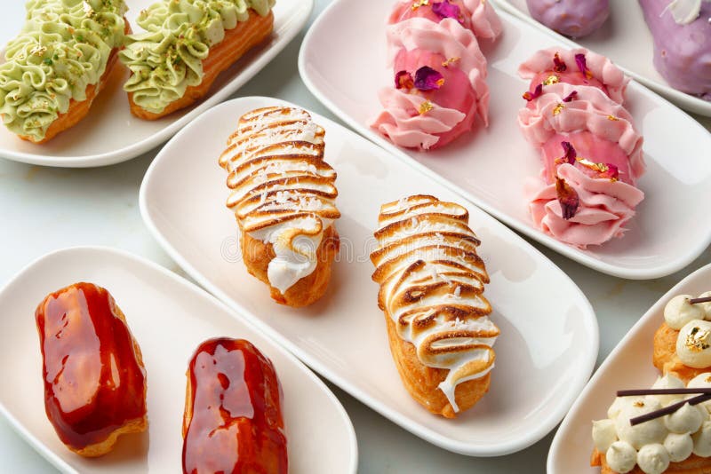Set of Colored Eclairs with Whipped Cream on White Plates Stock Photo ...