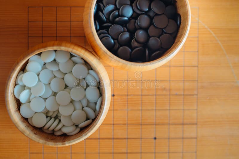 A Set of Go or Igo Game Stones in the Wooden Bowls on the Grid Table ...