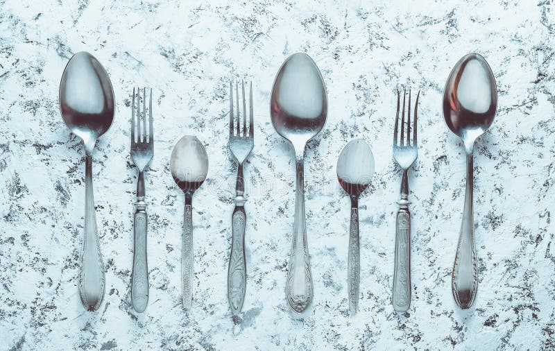 A Set of Grunge Metal Spoons and Forks on a White Concrete Surface. Top ...
