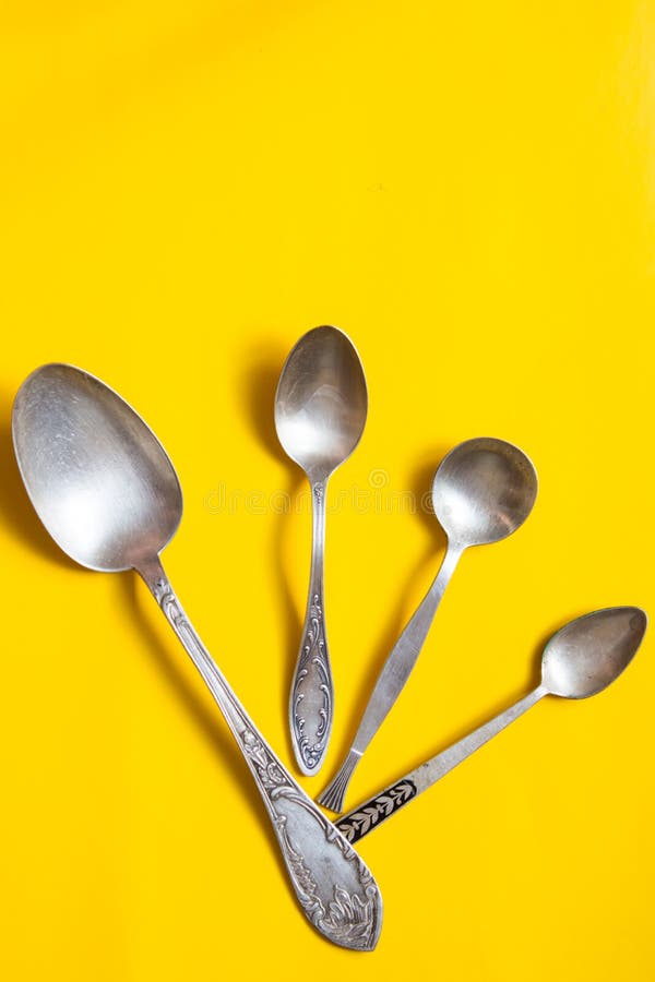 Set of Metallic Vintage Spoons on Yellow Background. Top View Stock ...