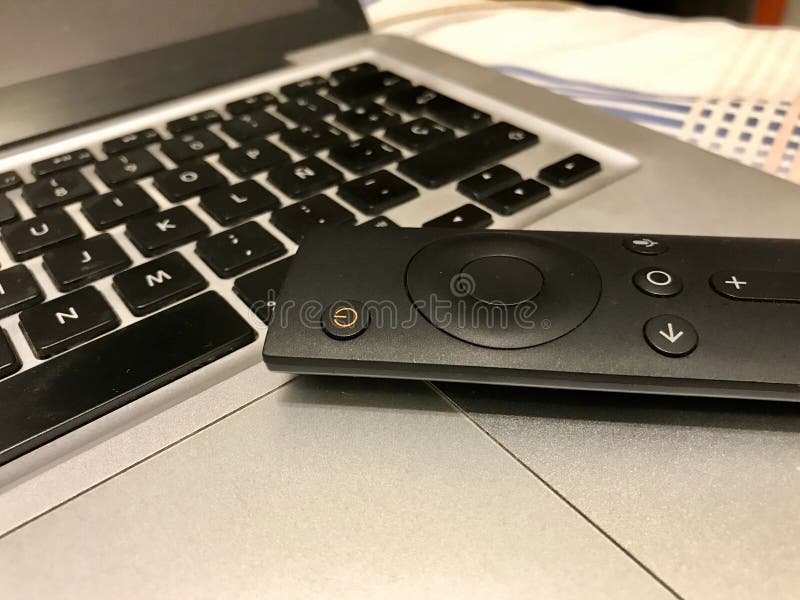 Set Top Box Television Remote Over a Silver Metallic Laptop Computer ...