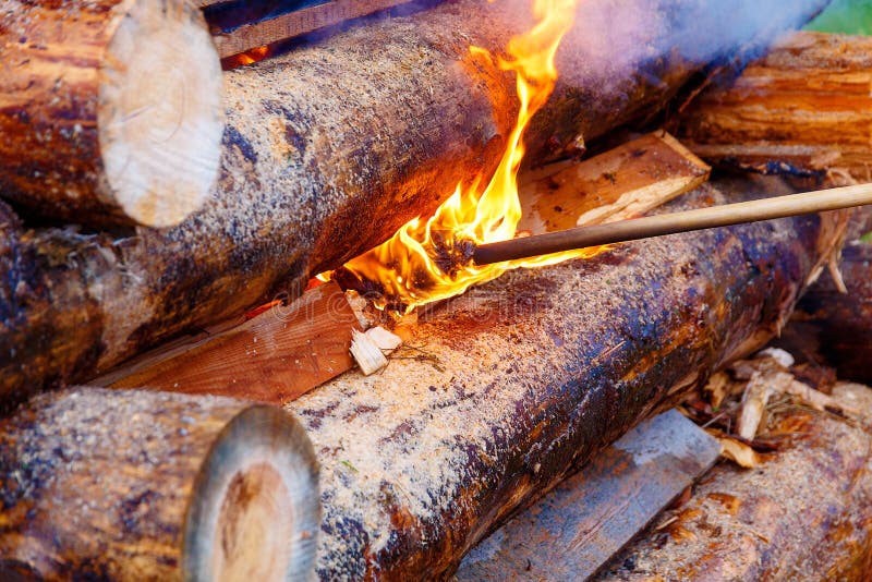 Setting Big Bonfire Made of Logs on Fire with Torch. Stock Photo ...