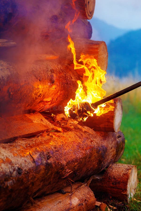 Setting Big Bonfire Made of Logs on Fire with Torch. Stock Photo ...