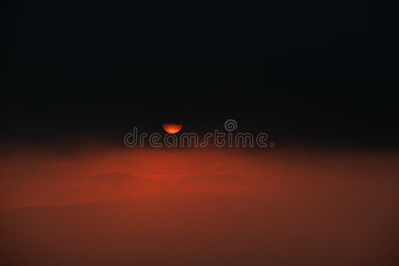 The Setting Sun Appears As a Sliver of Fire As it Descends Beneath a ...