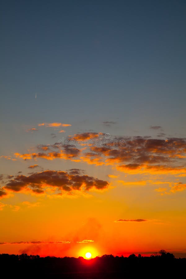 Setting Sun Backlights Small Clouds with Orange and White Stock Image ...