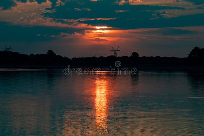 The Setting Sun Breaks through the Clouds Over a Power Line Stock Photo ...